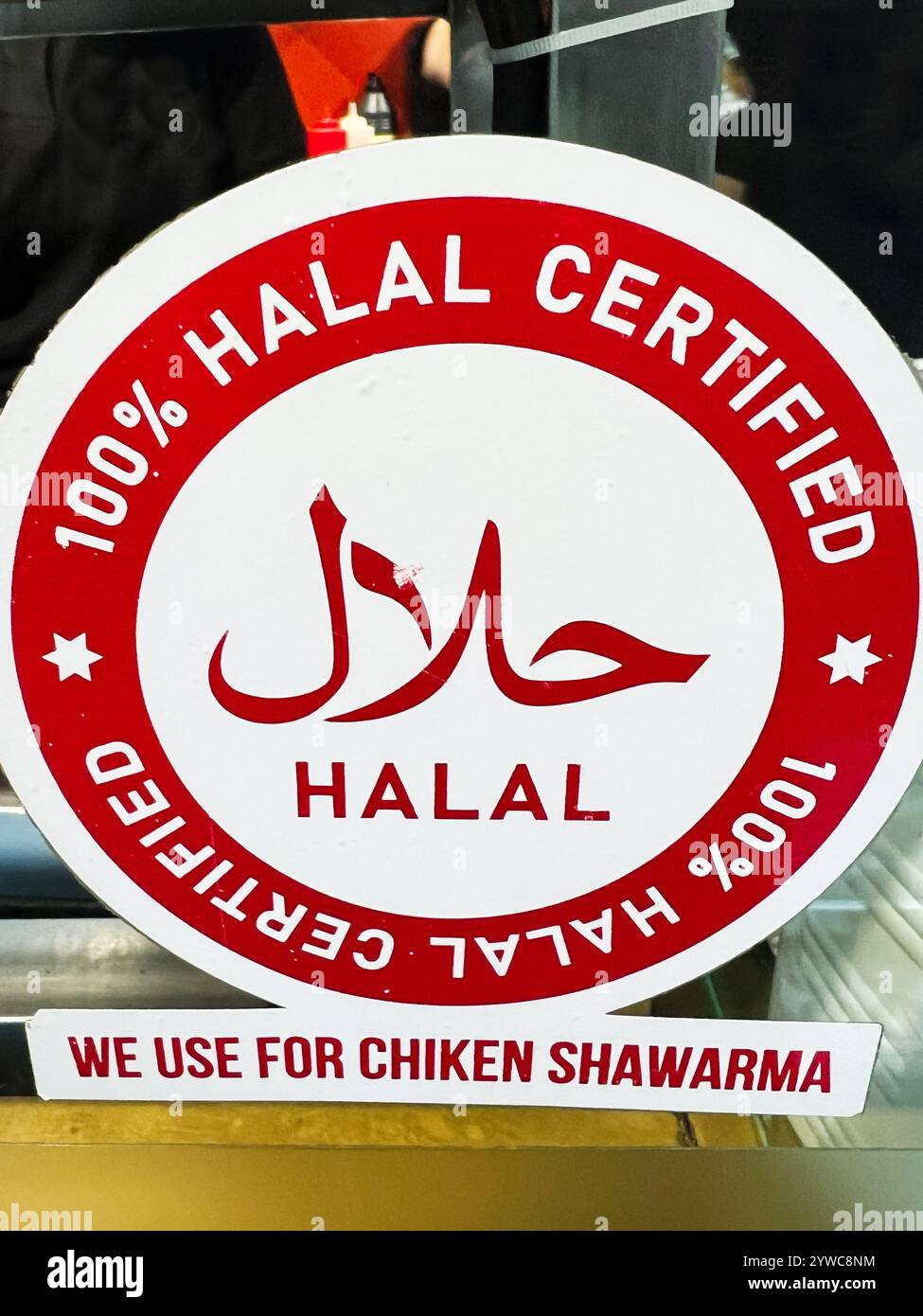 Sign indicating 100% halal certification is shown at a shawarma counter ...