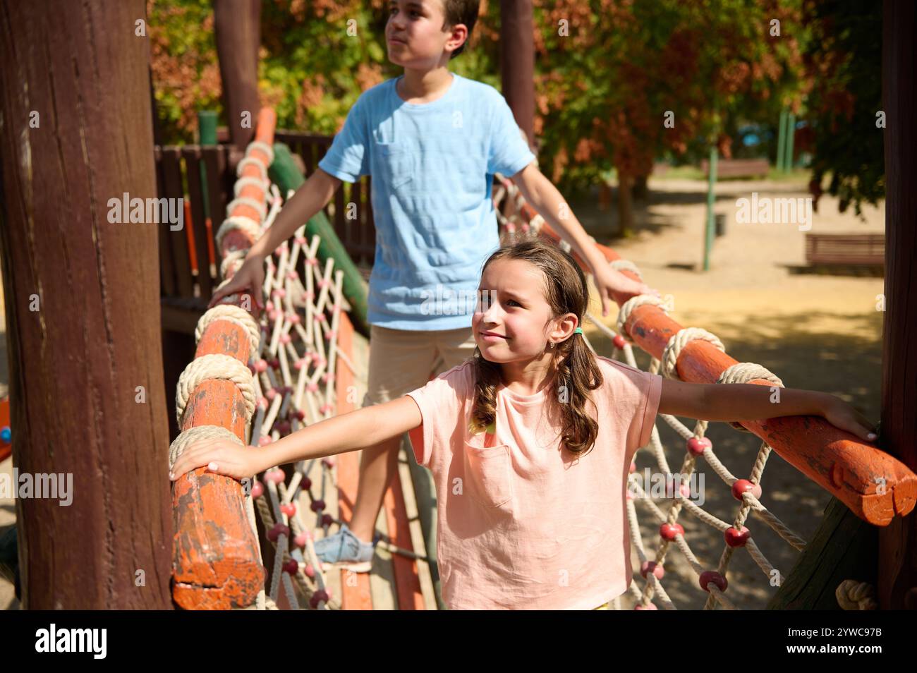 Two kids playing on a rope bridge at a playground, embracing adventure ...
