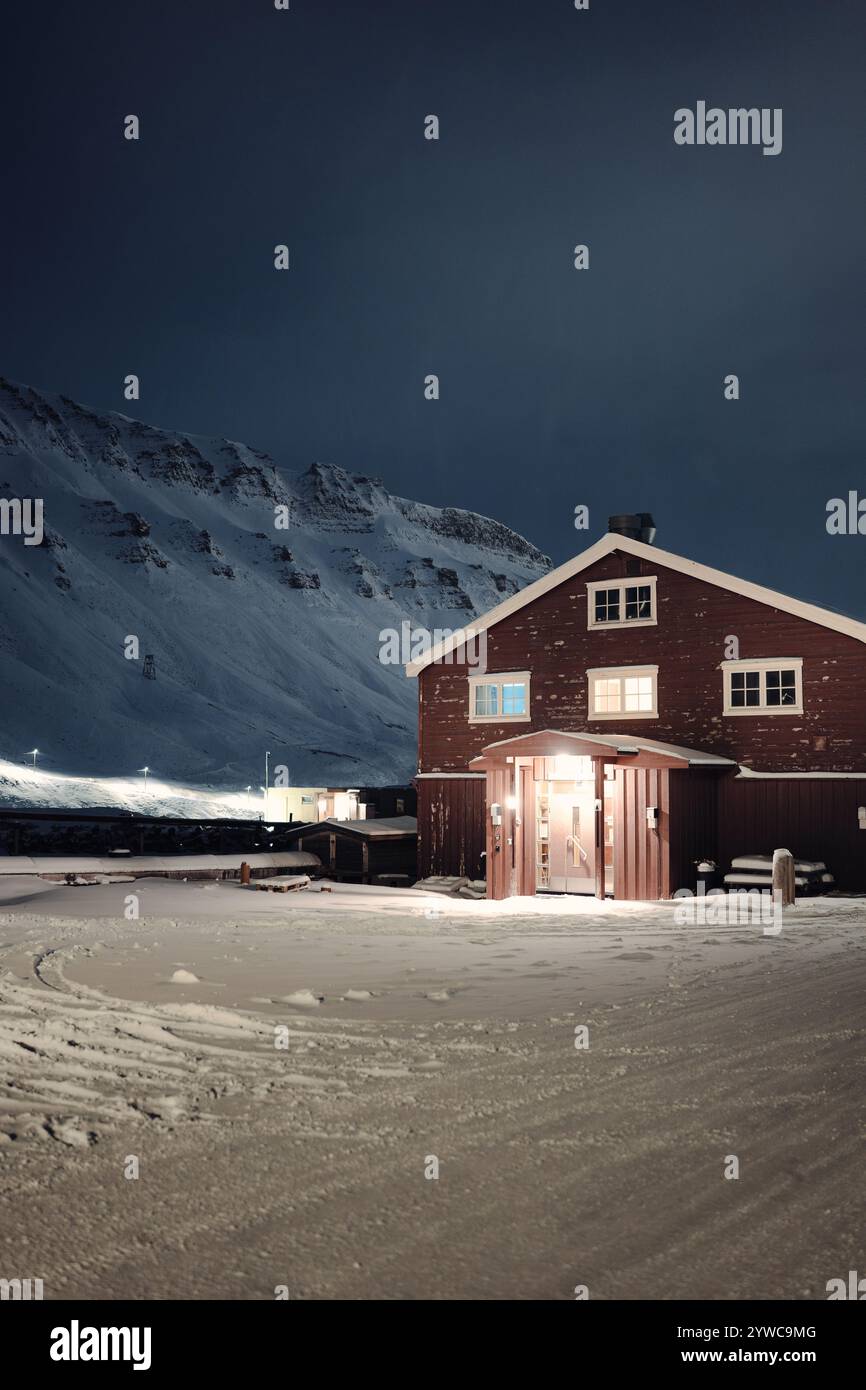 Brown wooden building underneath snowy mountains in Longyearbyen ...