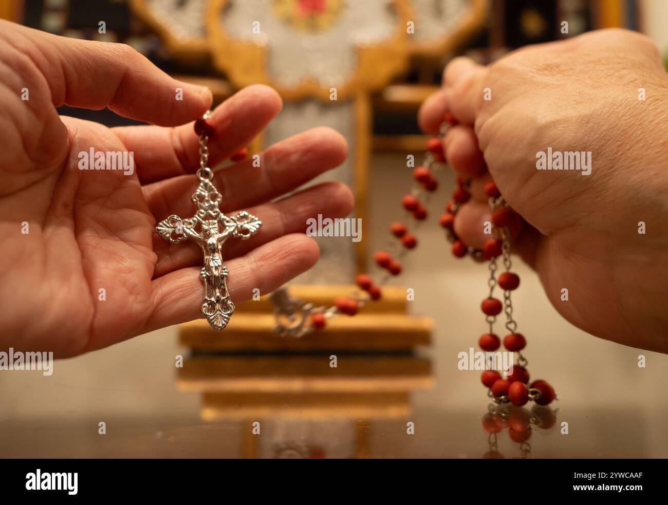 Senior Caucasian woman with wrinkled hands holding a red bead rosary in ...