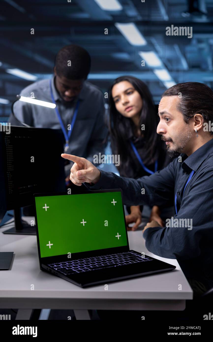 Multiethnic team of engineers in data center using system monitoring software on green screen ...