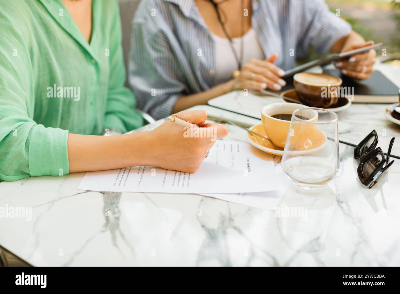 Two young women discussing work processes, signing documents and ...