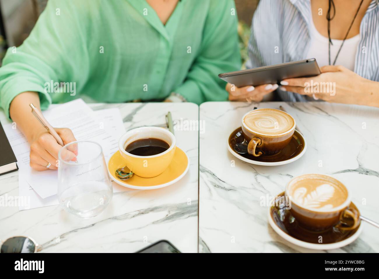 Two young women discussing work processes, signing documents and ...