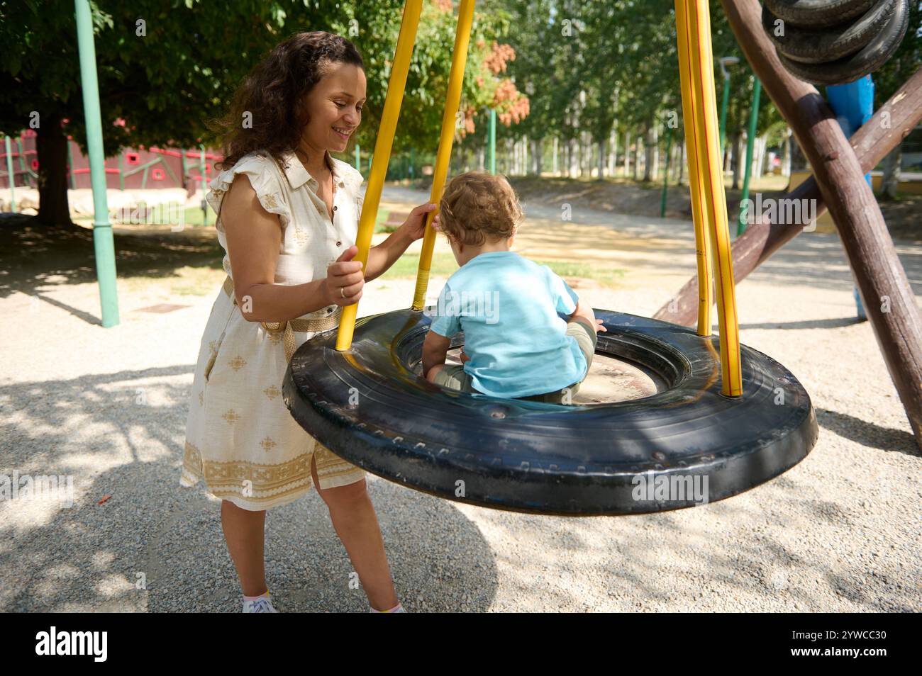A joyful scene of a mother and child playing on a tire swing in a park ...