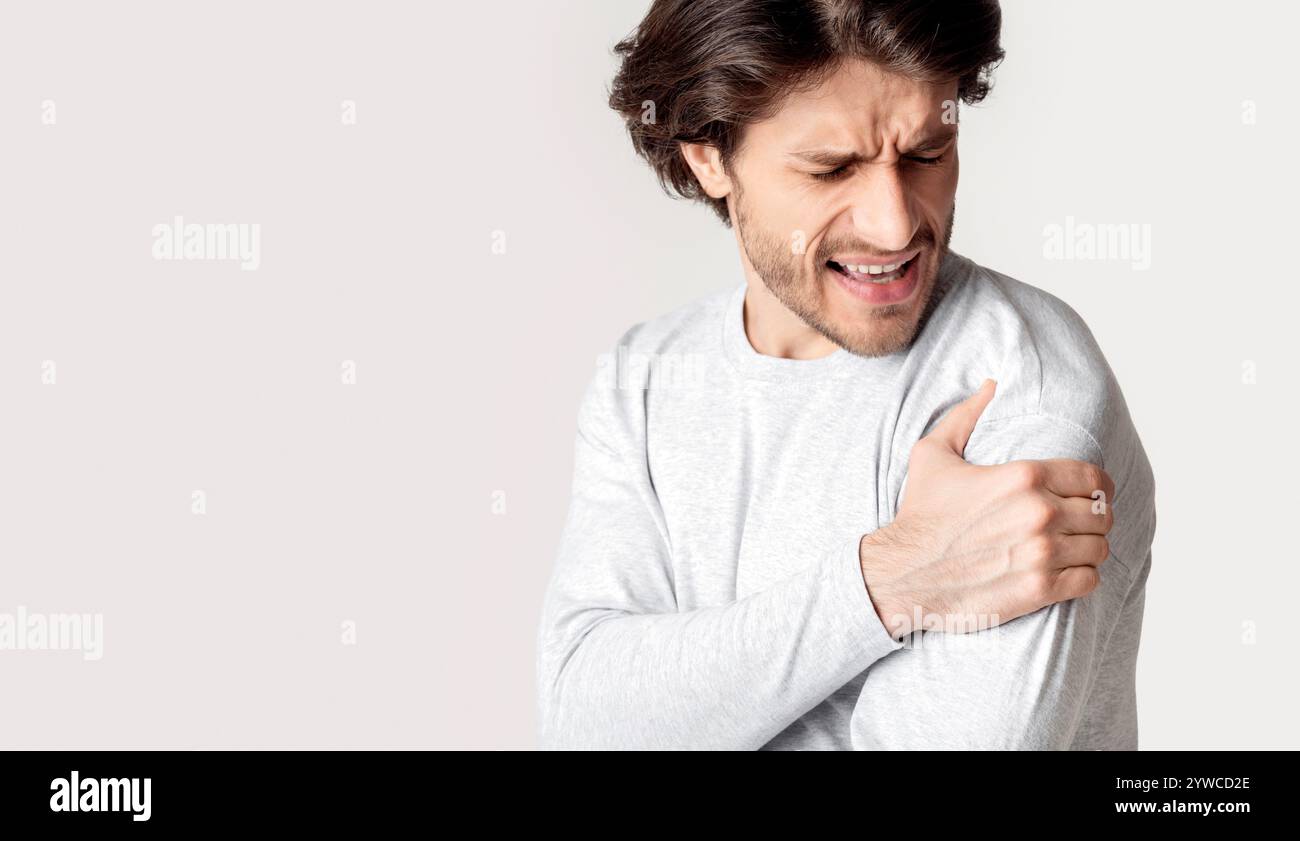 Shoulder pain. Guy presses hand to sore spot Stock Photo - Alamy