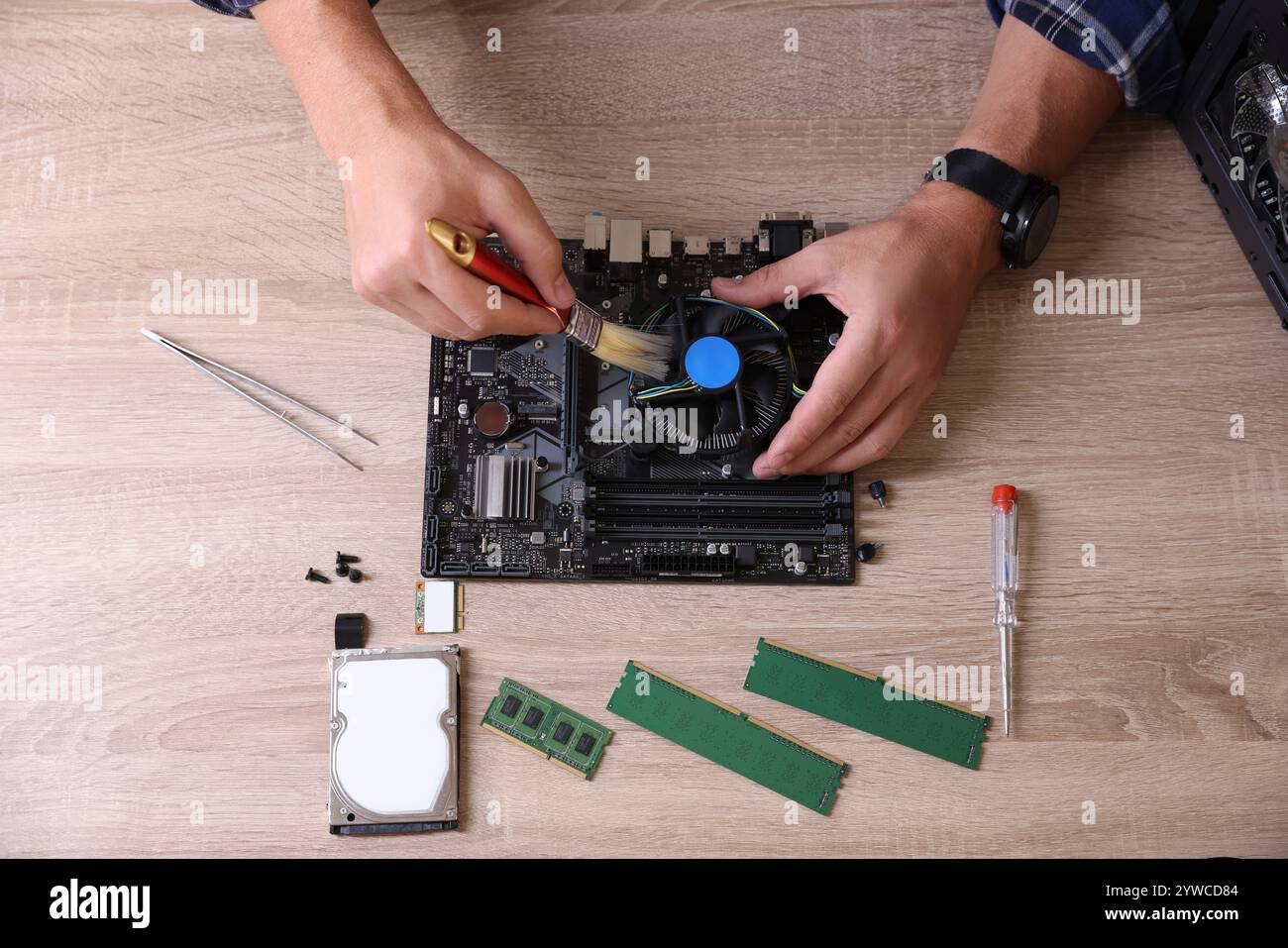 Man cleaning motherboard with computer chip at wooden table, top view ...