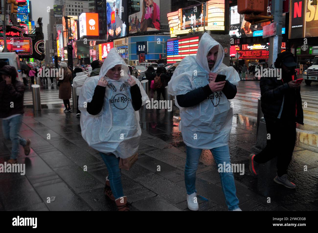 People walk wearing raincoats in a rainstorm in Times Square, Manhattan, New York City Stock ...