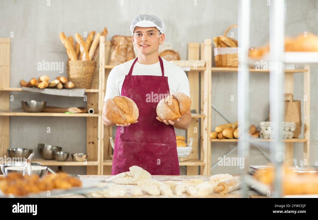 Bakery male employee holds ready made bread of bread in hands Stock ...