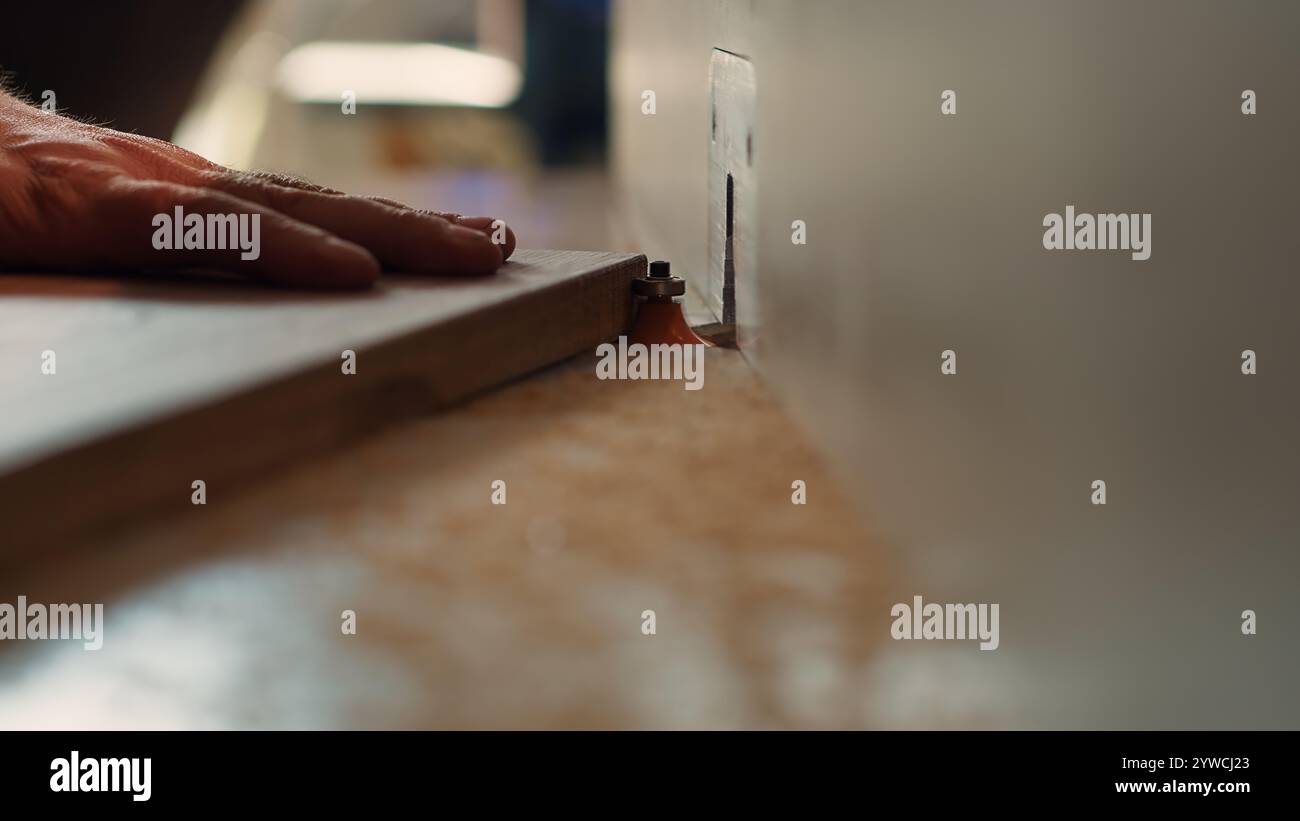 Carpenter in studio puts wood block through spindle moulder, creating ...