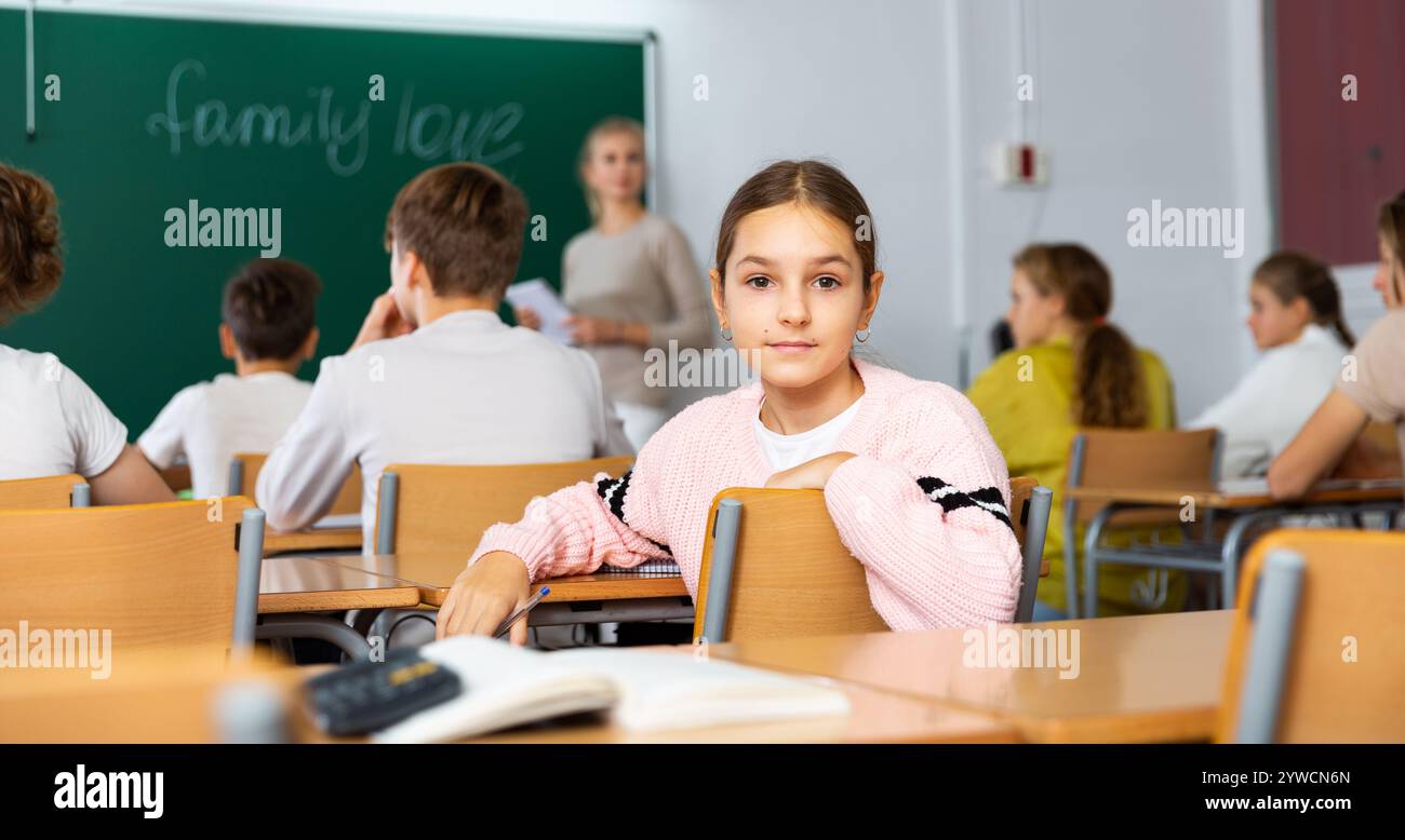 Girl turned around and looking at camera during lesson in classroom ...