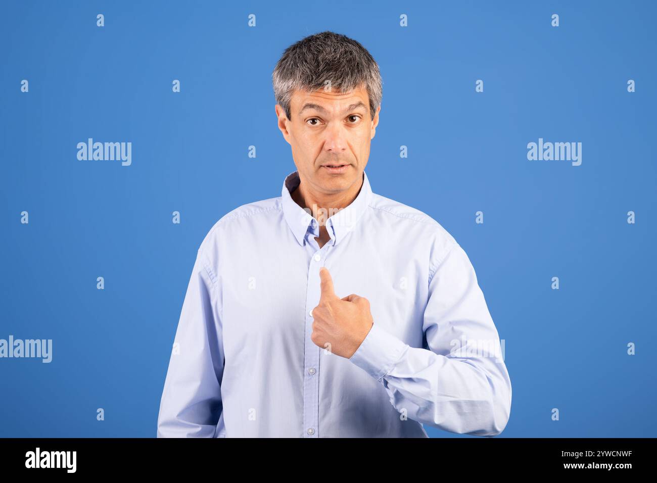 Mature European man gestures to himself in a relaxed studio setting ...