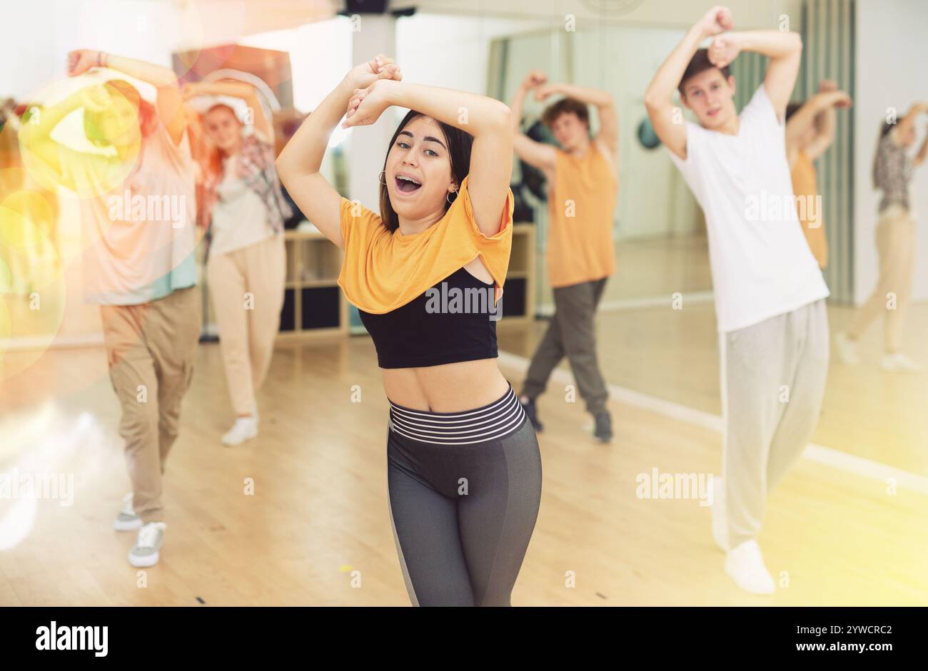 Happy brunette teenage girl practicing vigorous dance with group Stock ...
