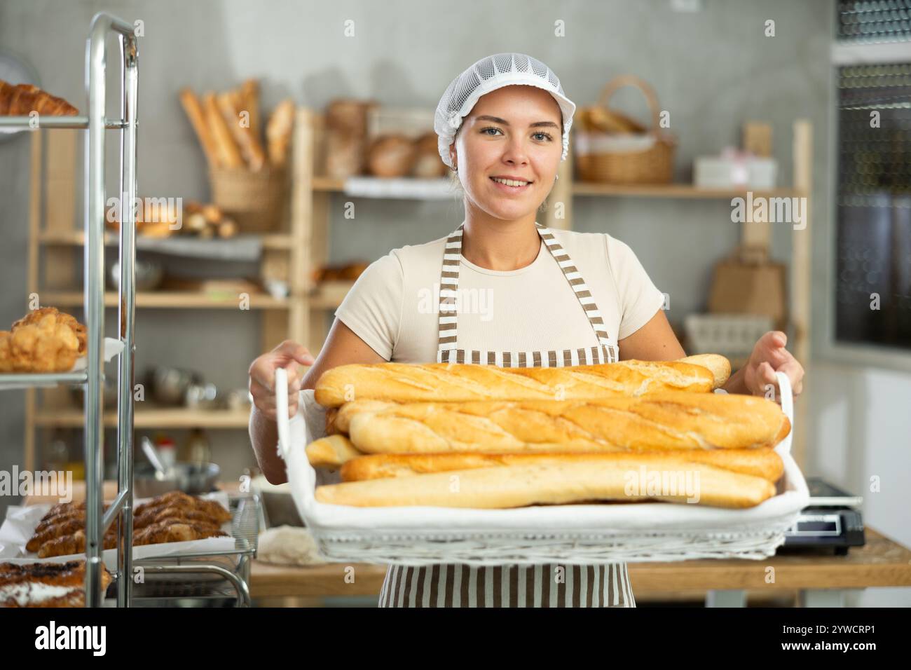 Smiling female baker presenting fresh baguettes in bakery Stock Photo ...
