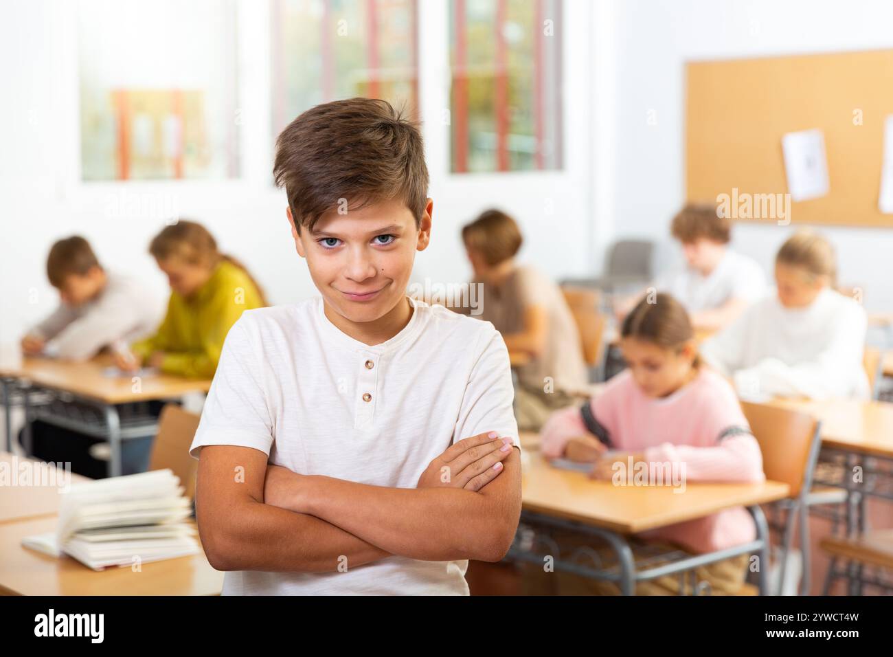 Happy boy stands in a school class against background of classmates ...