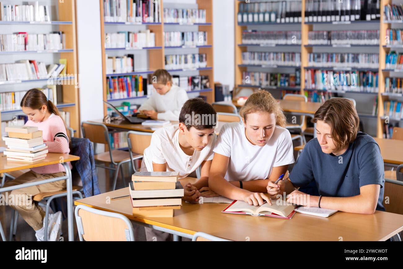 Teenage students working in groups in library Stock Photo - Alamy