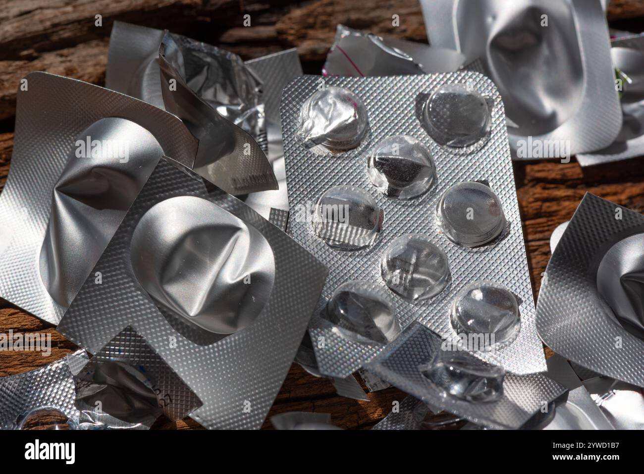 Empty blister packs scattered on wooden surface, highlighting waste and ...
