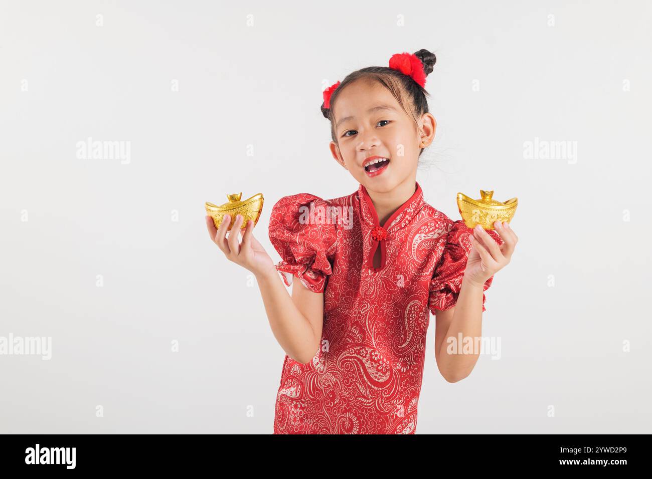 Festive Asian child in a red cheongsam dress holding a gold ingot ...