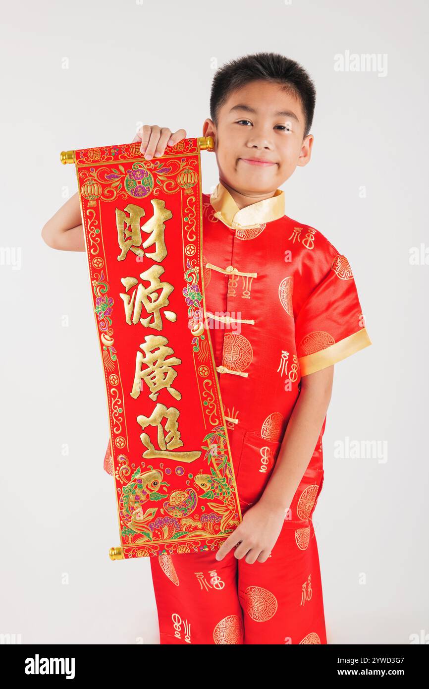 Asian boy in festive red qipao holds Chinese New Year couplets with "FU ...