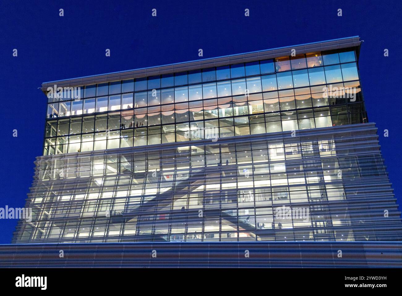 Visitors inside the Munch museum illuminated against the night sky ...