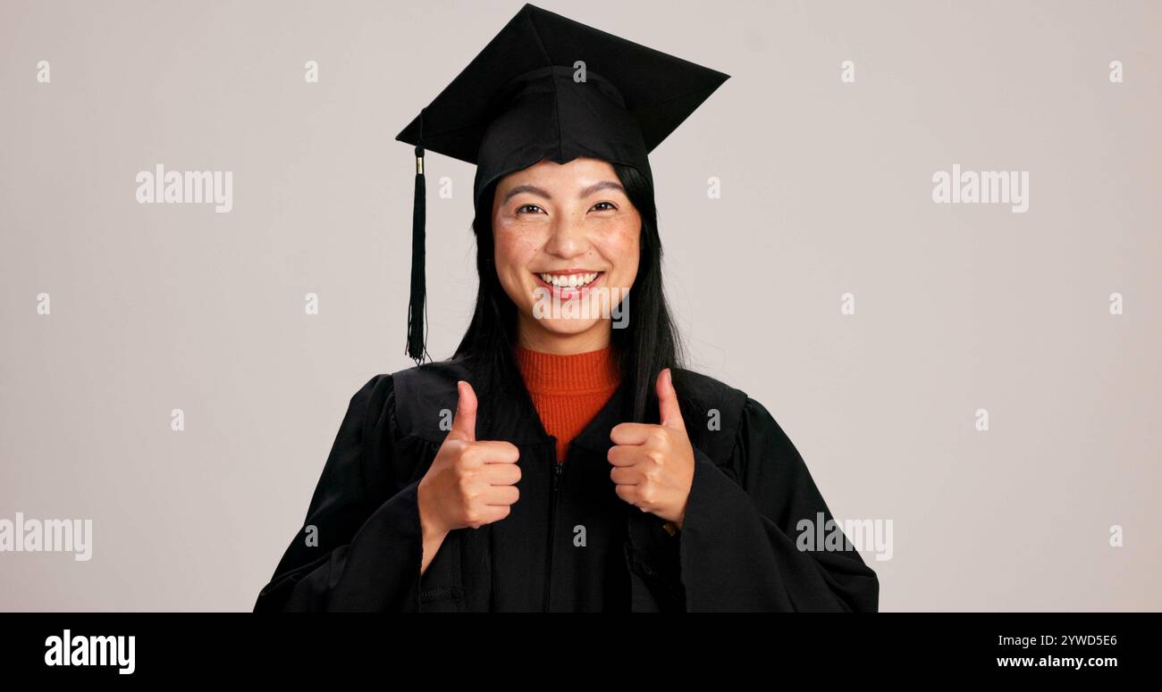 Thumbs up, graduation and smile with portrait of asian woman in studio ...