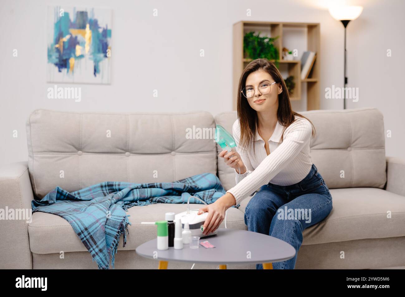 Young woman holding a mask nebulizer inhaling fumes medication into ...