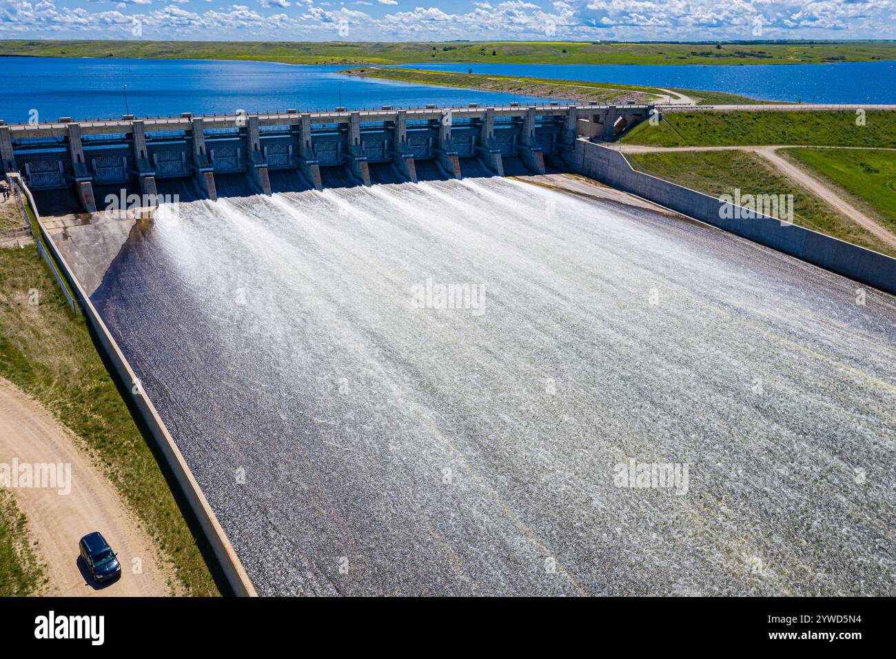 A large body of water with a dam and a car driving by. The water is ...