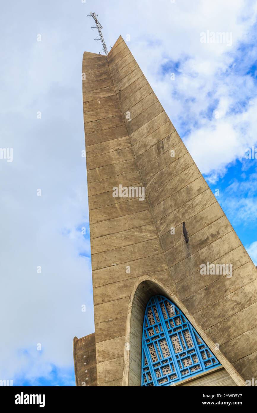 A large, brown building with a blue window and a cross on top. The ...