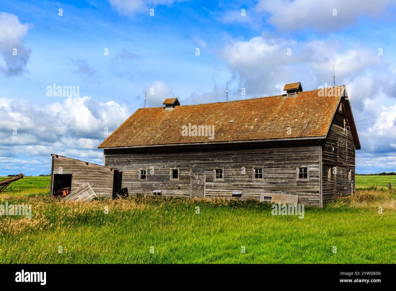 A large, old, wooden barn with a lot of windows and a slanted roof. The ...