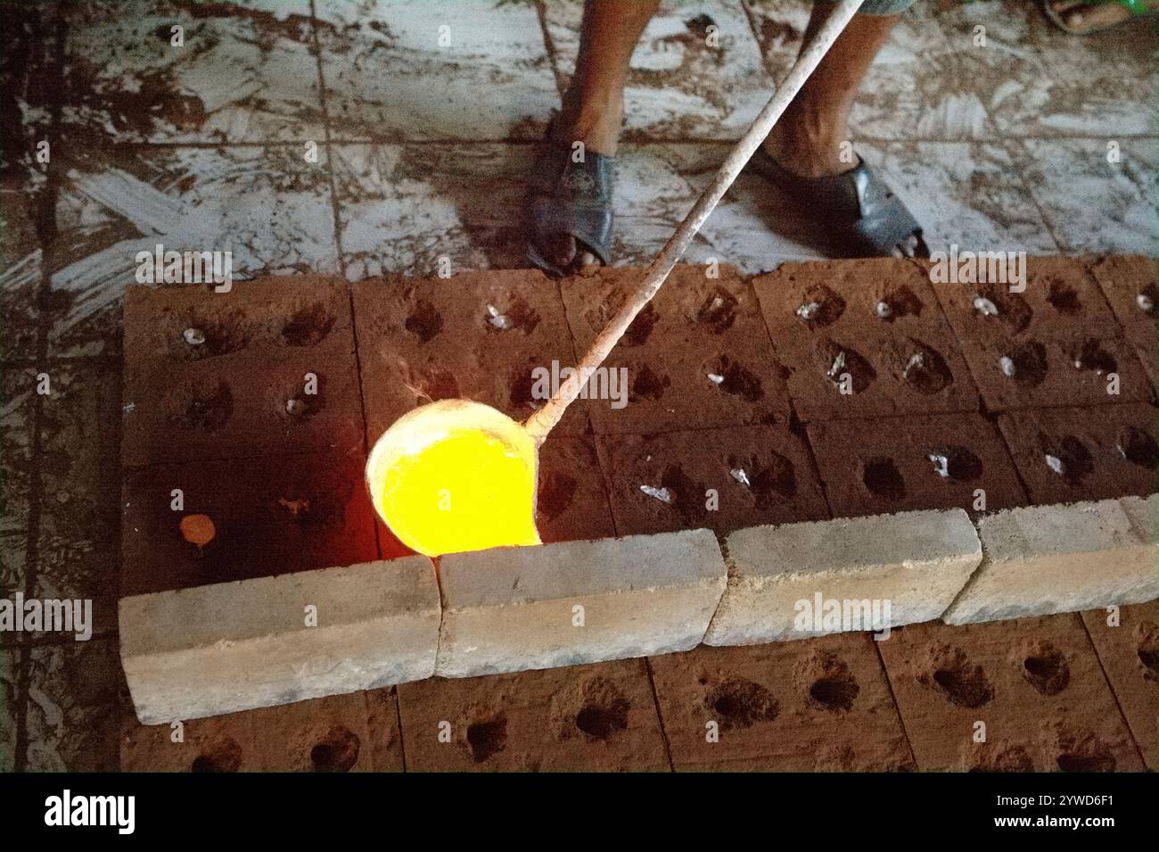 A worker molding liquid metal as a part of production process in the ...