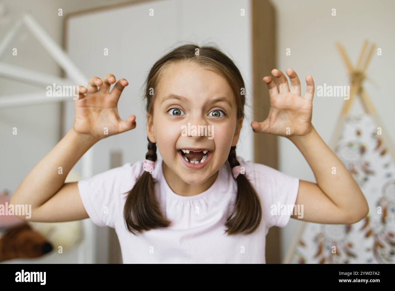 Portrait of playful little Caucasian girl with braided hair and gaps ...