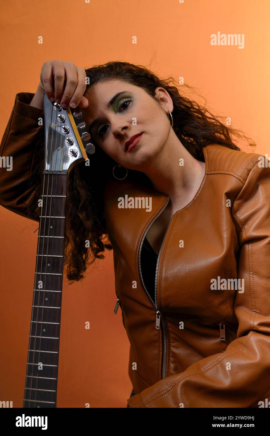 Young woman musician with curly hair and leather jacket posing with her ...
