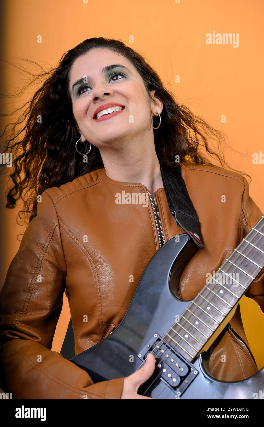 Female musician with long, curly hair playing electric guitar and ...