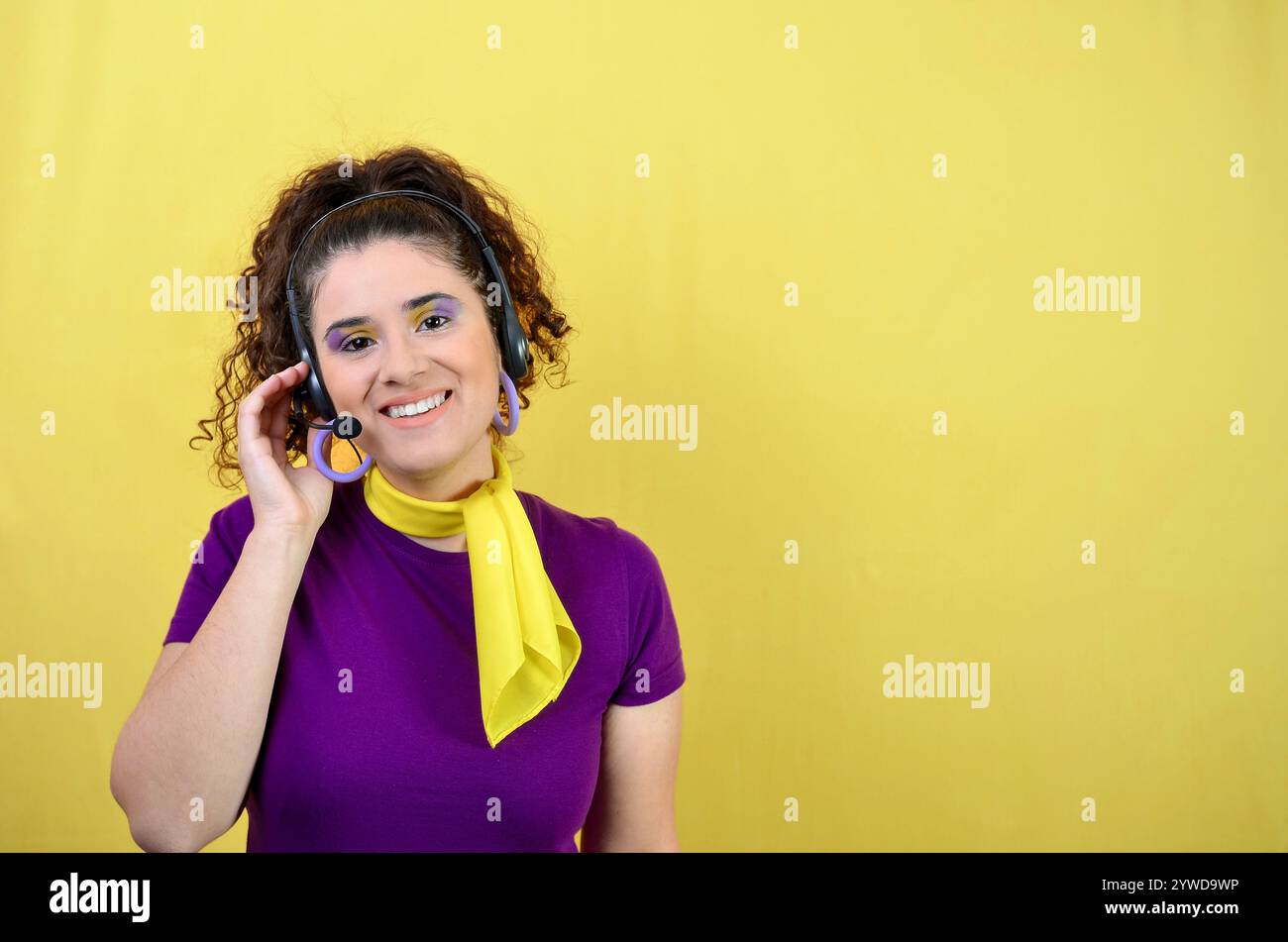 Friendly telemarketer wearing headset and smiling on yellow background ...