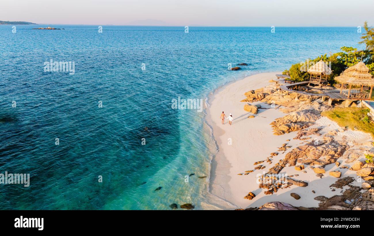 Soft white sands meet crystal-clear waters as visitors stroll along the ...