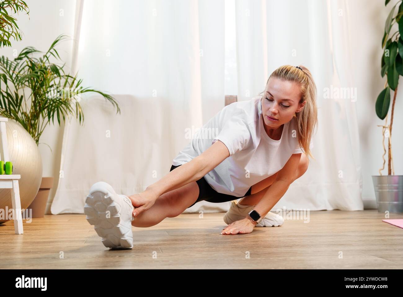 Woman performing a stretching exercise in a bright indoor Stock Photo ...