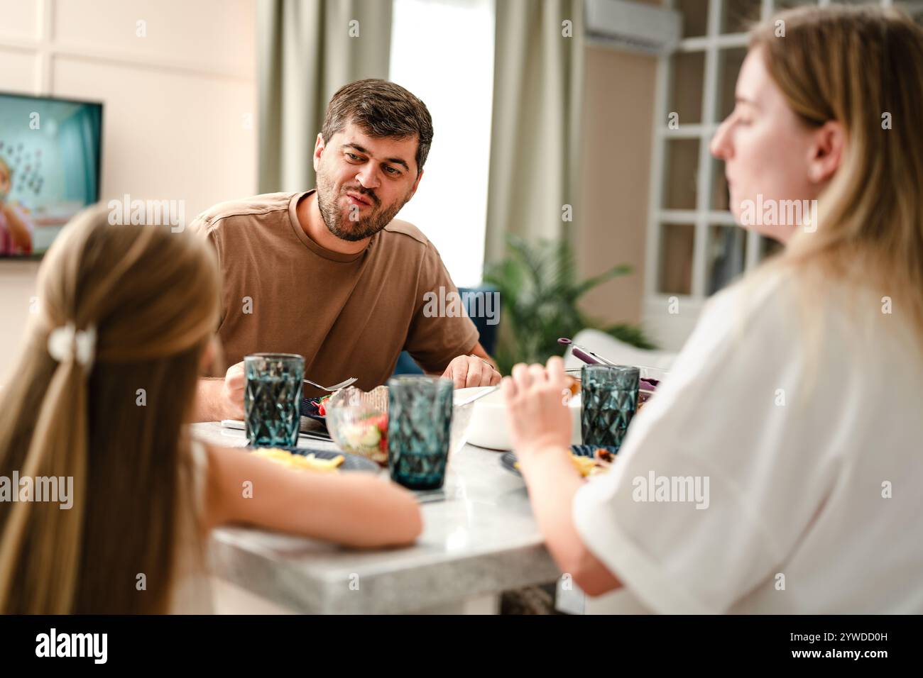 A family sits around a table in a home, enjoying a meal Stock Photo - Alamy
