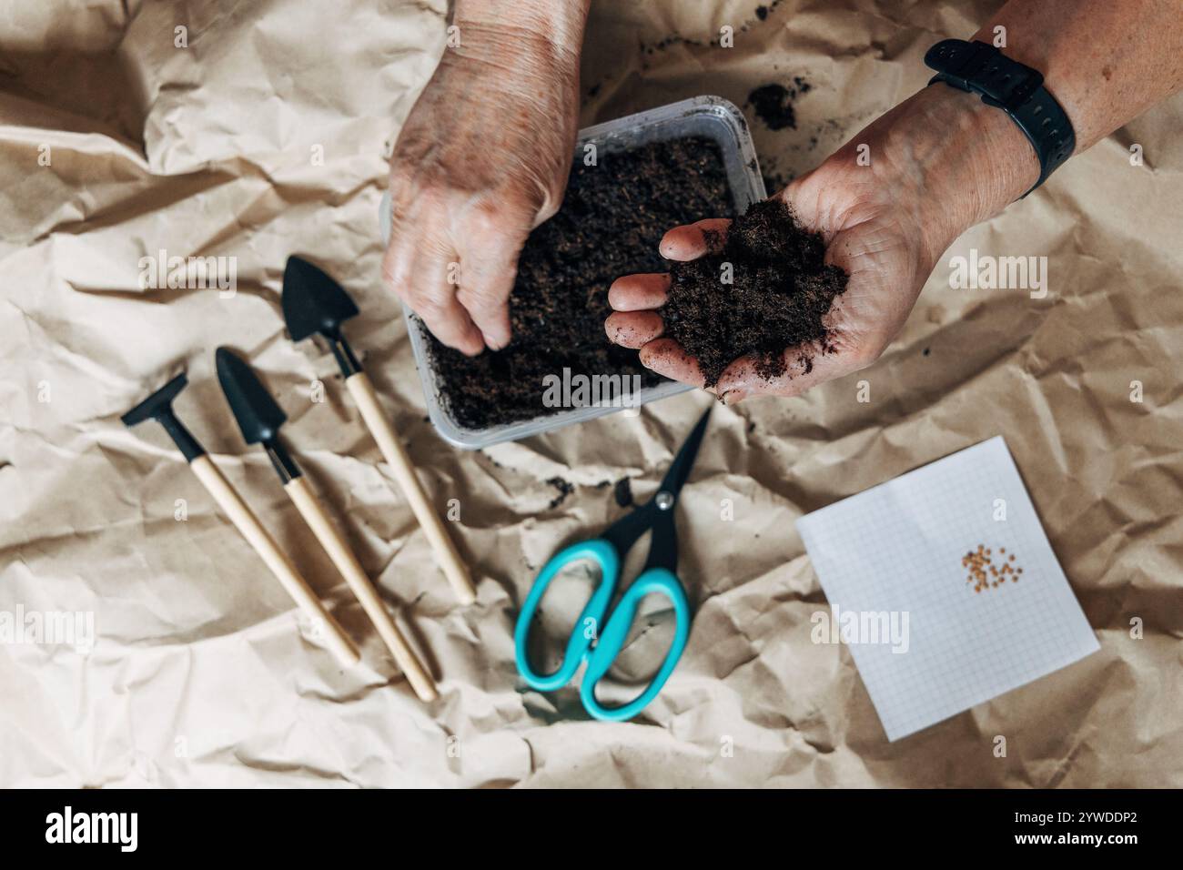 Kraft paper background, fertile soil and garden tools, top view. Hands ...