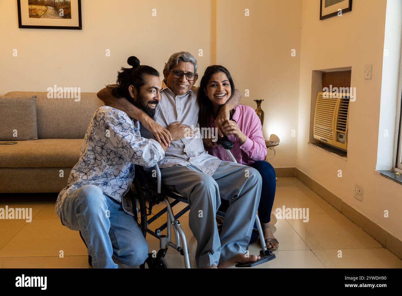 Happy young indian couple taking care of disabled father on wheel chair ...