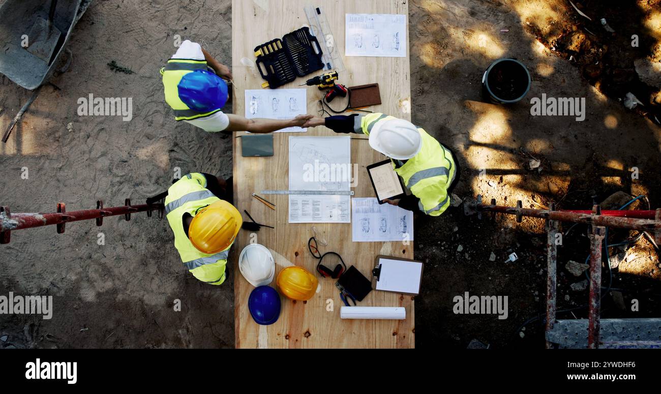 Blueprint, construction site and men at table with handshake ...
