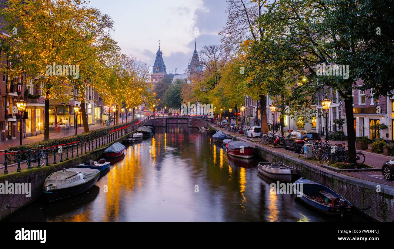 As twilight descends on Amsterdam, vibrant autumn leaves frame the calm ...