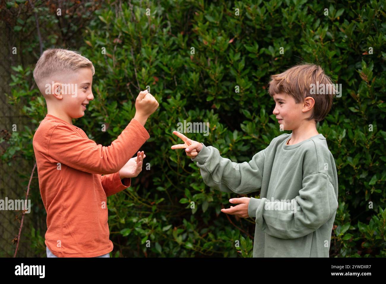 Two cheerful boys are having fun playing rock paper scissors in a ...