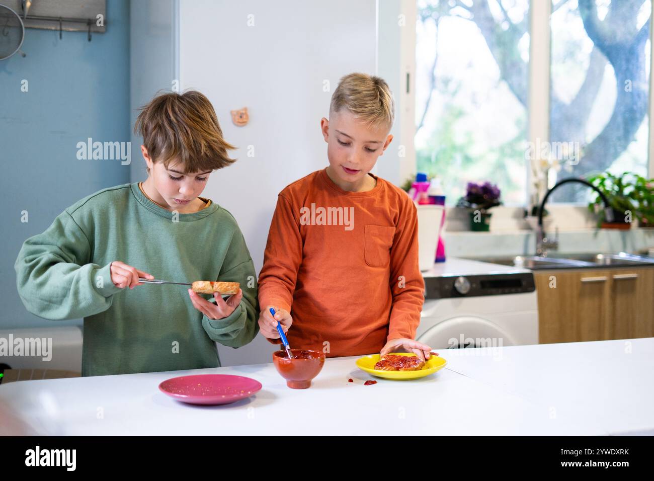 Two brothers spreading jam on toast, enjoying a simple breakfast ...