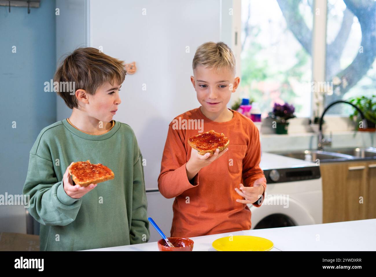 Two young brothers enjoying a simple breakfast of toast and jam in a ...