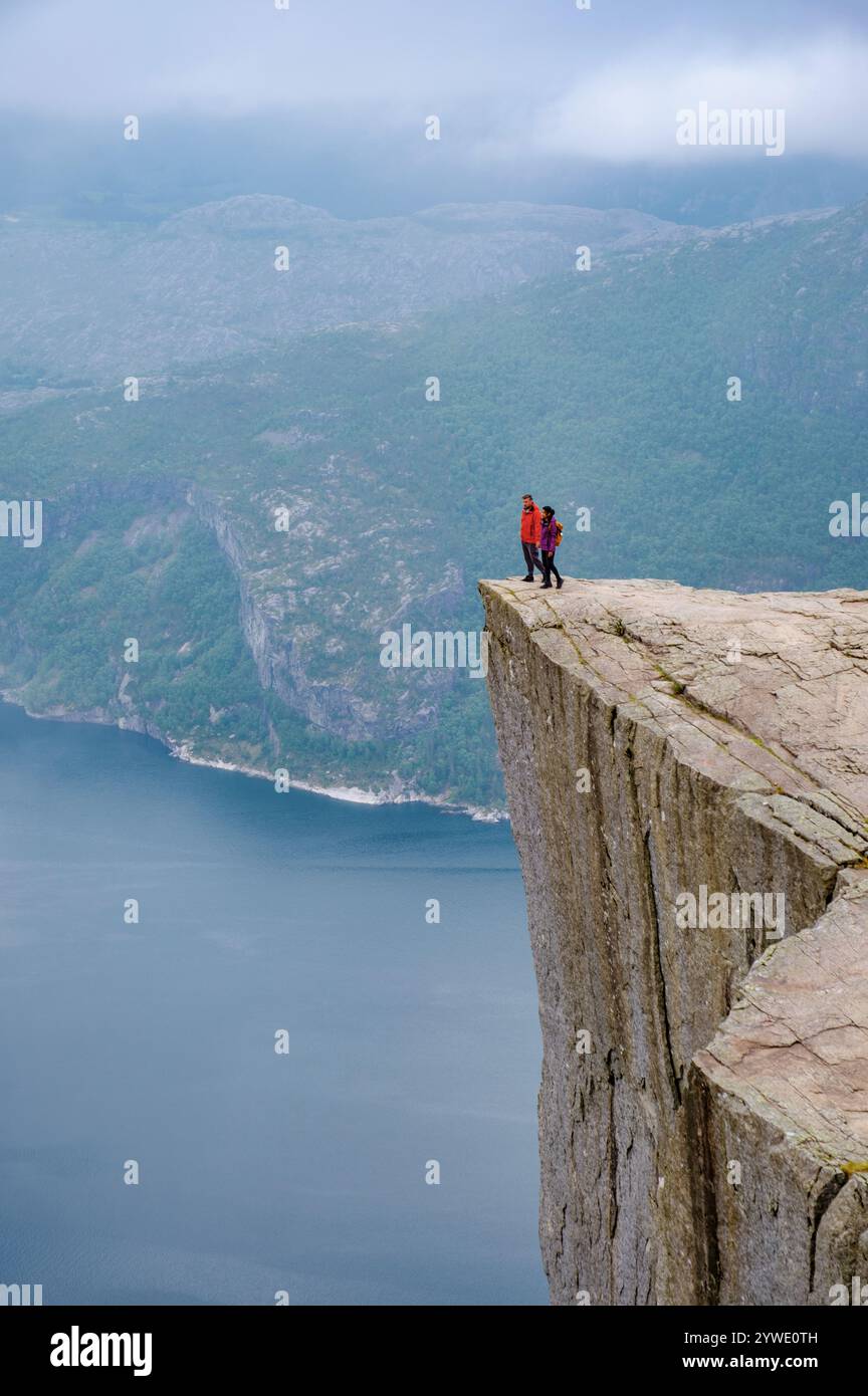 A couple stands on the edge of a cliff, taking in the breathtaking view ...