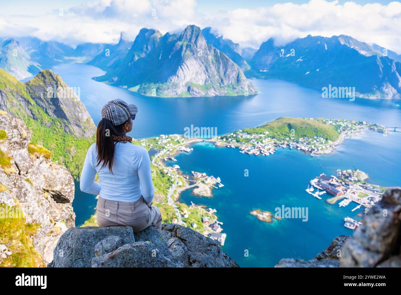 An Asian woman sits on a rocky cliff overlooking a stunning view of the ...