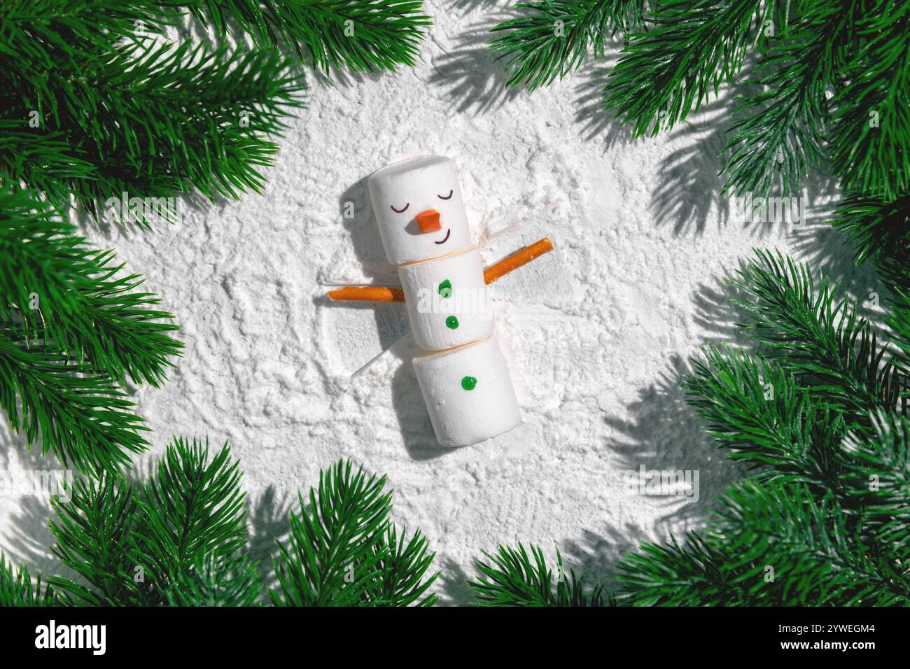 Funny marshmallow snowman lying on snow, creating a snow angel with ...