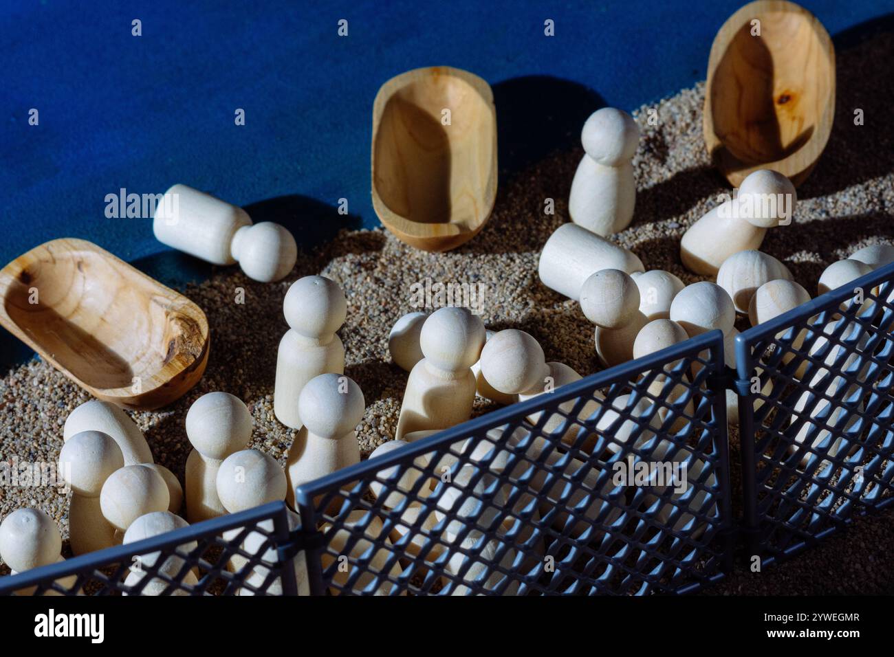 Hope and Barriers: Wooden Figures and Boats on the Sand Stock Photo - Alamy