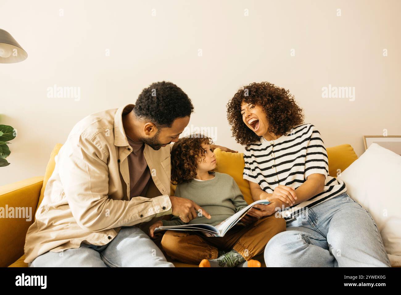 Family enjoying leisure time reading and laughing on a sofa at their ...