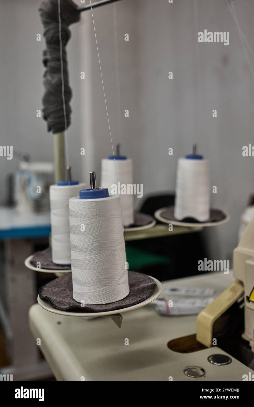 Several cones of white thread are set up on an industrial sewing ...