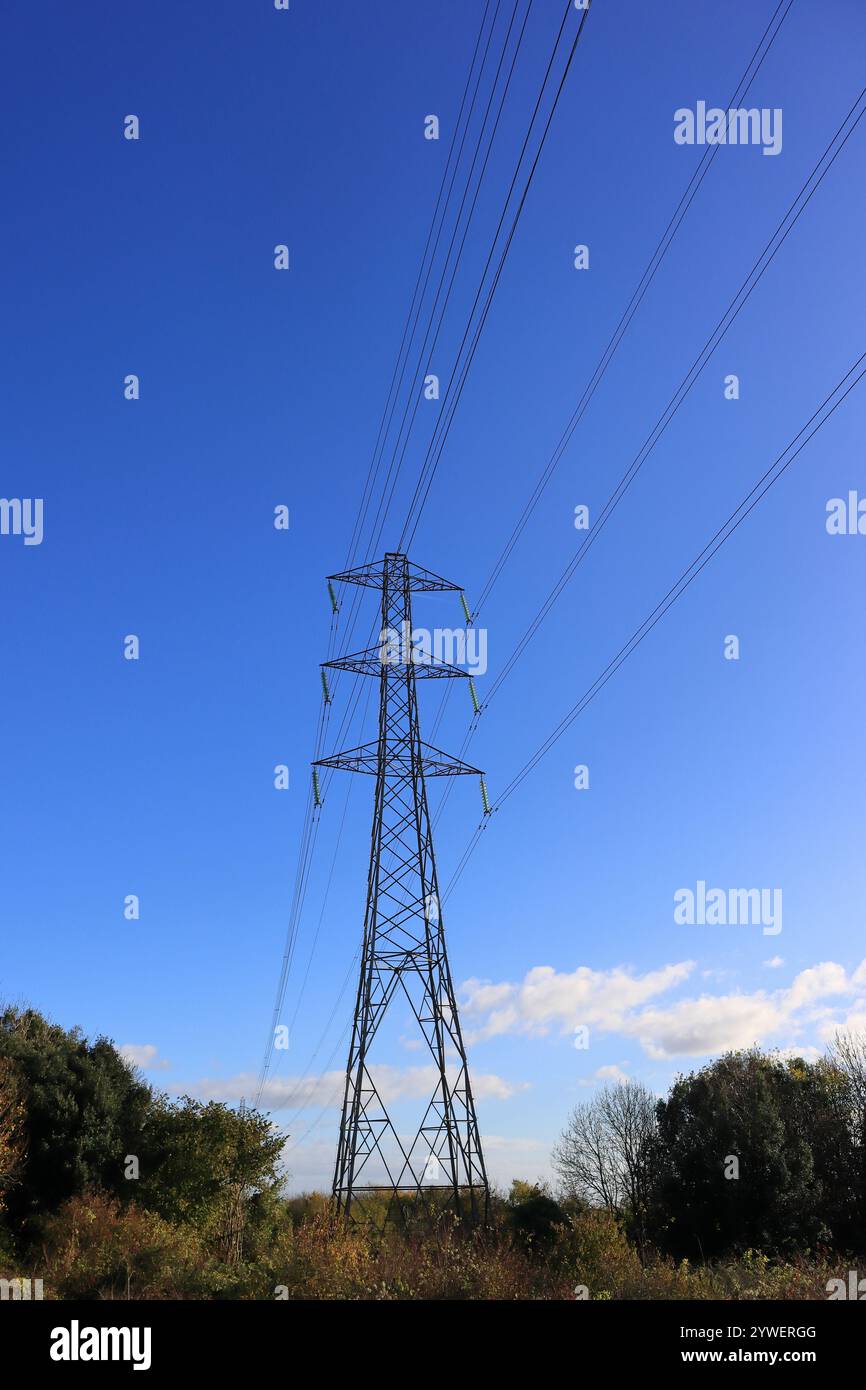 A tall electrical pylon with the cables overhead, set against a blue ...